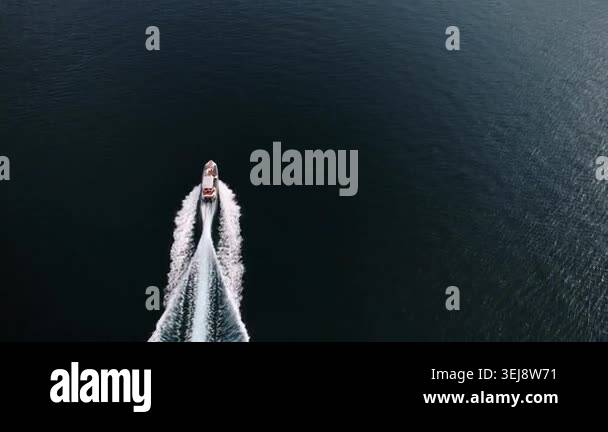 Aerial view caucasian man piloting speedboat over deep dark water, lone ...