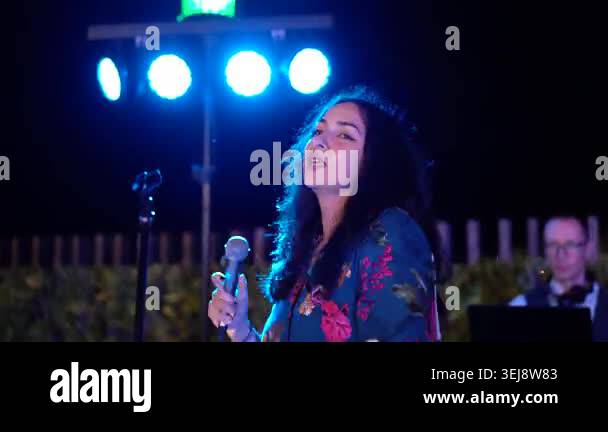 South Asian female vocalist under stage lights energetic nighttime ...