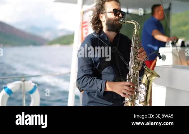 White saxophonist boat performer cruising sea on sunlit deck with ...