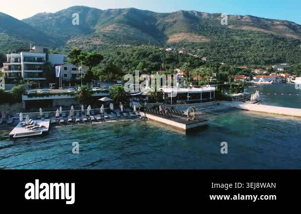 Aerial coastal resort with private pier and beach, turquoise bay dotted ...