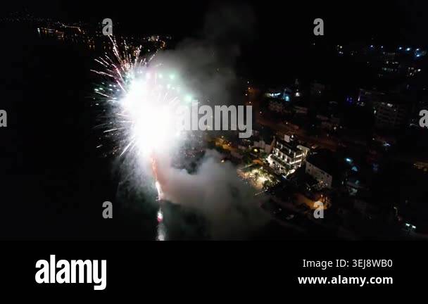 Aerial golden fireworks shower over town, warm amber bursts fill night ...