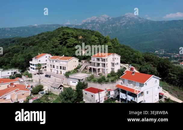 Aerial hillside village with red roofs overlooking rugged mountain ...