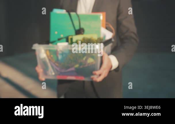 suit carrying clear box of office belongings at sunset, walking past ...