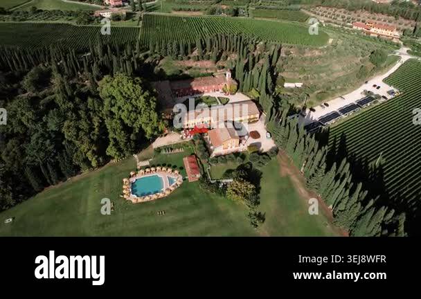 Aerial resort pool surrounded by lawn and umbrellas, blue water and ...