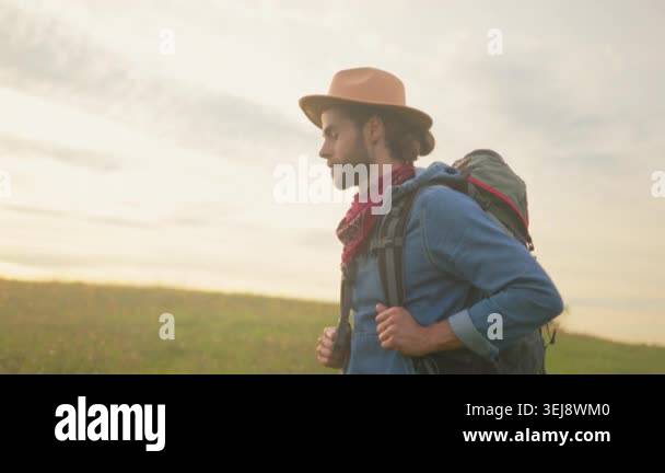 white male hiker in golden meadow at sunset walking with backpack ...
