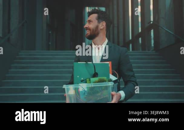 smiling caucasian businessman carrying box down steps of modern office ...
