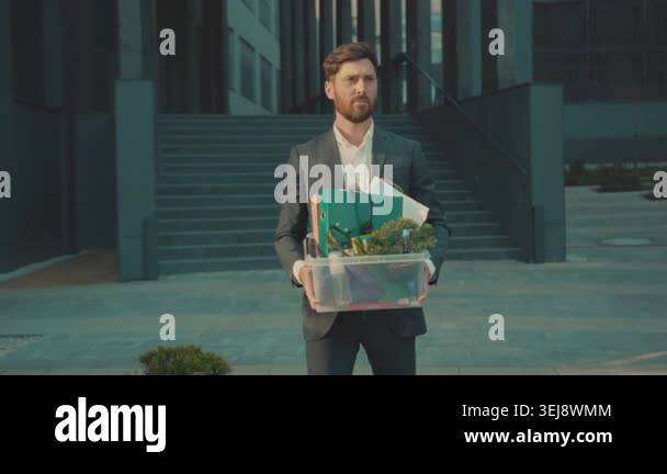 caucasian entrepreneur leaving office with packed box and plant ...