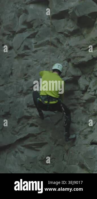 unspecified male climber on textured rock, neon green top and white ...