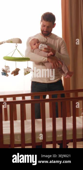 father holding baby by crib soft morning light wooden crib green mobile ...