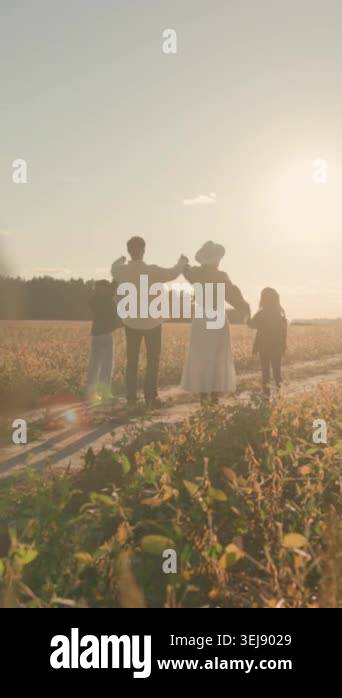 sunset field family white parents walking holding hands down dirt path ...