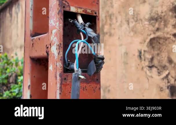 Messy exposed electrical wiring inside rusty outdoor pole close up ...