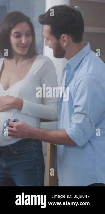 expectant white couple placing tiny baby shoes on pregnant belly in ...