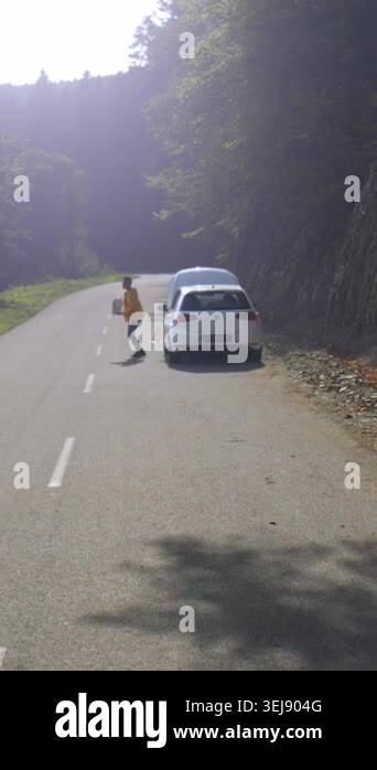 white hatchback parked on winding road as person in yellow jacket ...