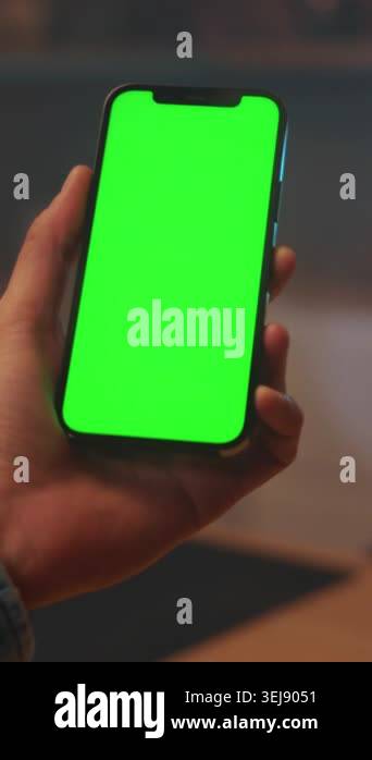 close up hand touching smartphone green screen, warm office lighting ...