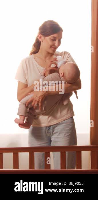 mother feeding baby with bottle soft backlight wooden crib smiling ...