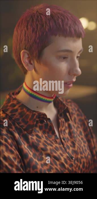 Shorthaired person with rainbow choker, contemplative portrait in warm ...