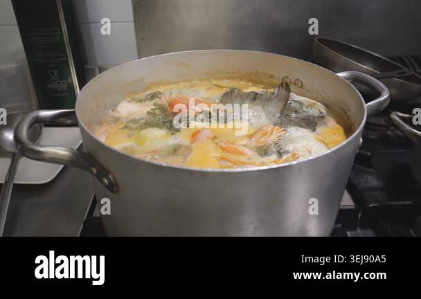Close up of a chef cooking a hearty seafood stew with fish, shrimp, and ...