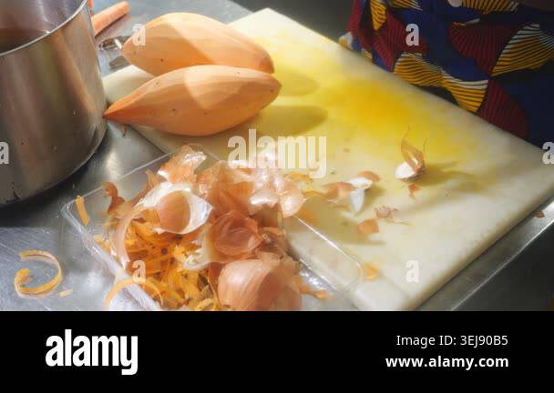 A chef in a professional kitchen meticulously peels sweet potatoes and ...