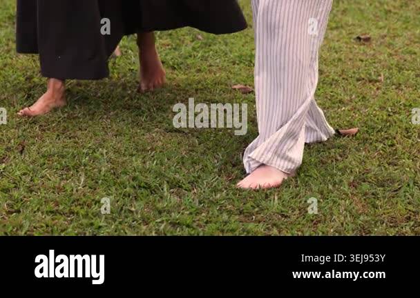 Two barefoot women walking on grass earth connection outdoor concept ...