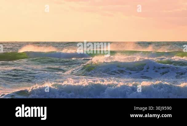Powerful ocean waves breaking on the shore during a golden sunset ...
