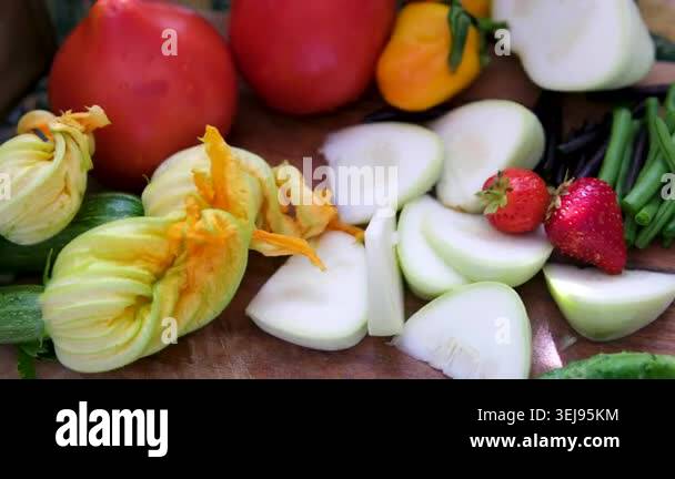 Fresh homegrown vegetables arranged on a wooden board in warm sunlight ...