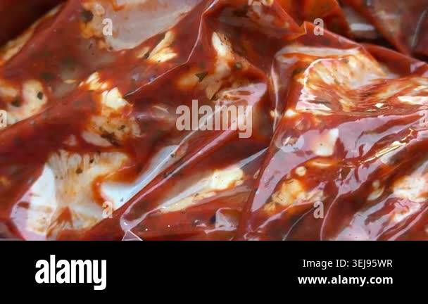 Raw marinated meat with rich orange red spices packed in plastic bags ...