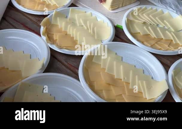 Assorted cheese pieces placed onto disposable white plates during ...
