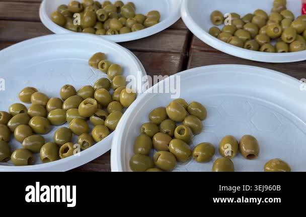 Outdoor picnic table with pitted olives arranged on plastic plates for ...
