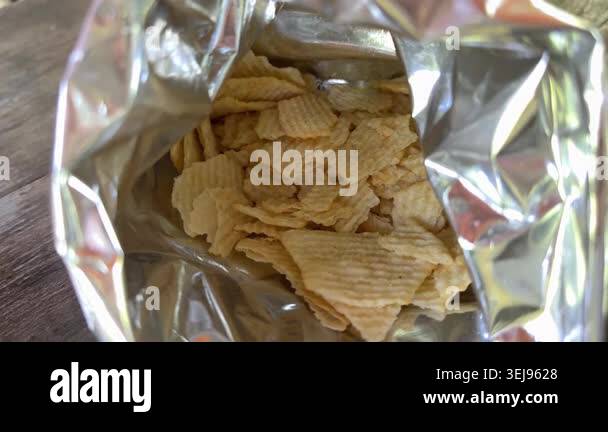 Golden crunchy potato chips inside opened foil package with detailed ...