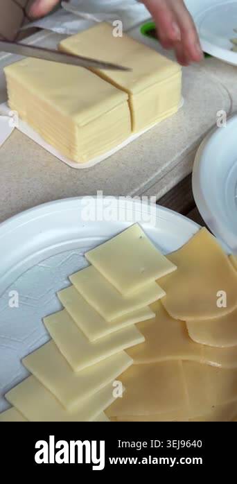 Assorted cheese pieces placed onto disposable white plates during ...