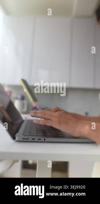 Side view hands on laptop at kitchen counter, smartphone on tripod, mug ...