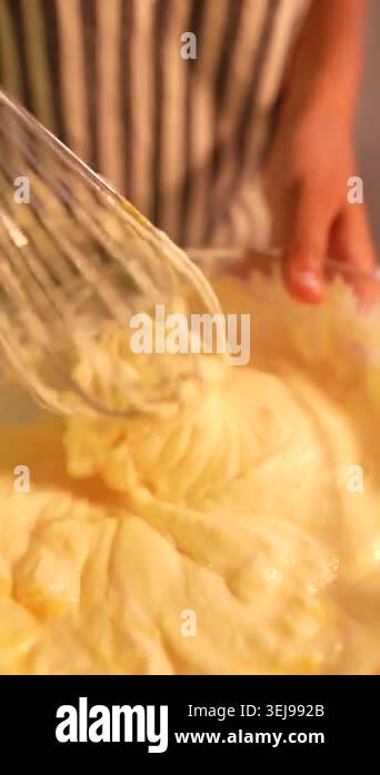 Closeup whisk creating airy batter peaks, striped apron hands lifting ...