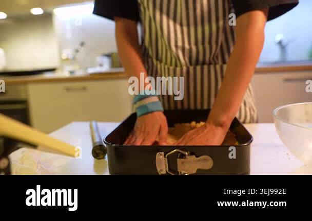 Hands pressing crust into springform pan on kitchen counter. Focused ...
