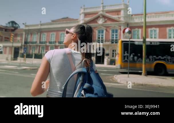 Sunlit boulevard young woman drinks from colorful reusable bottle ...