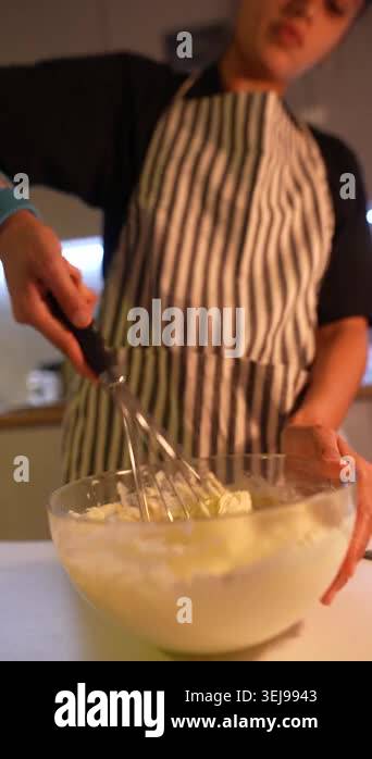 Closeup kitchen whisk mixing batter, striped apron hands whipping ...