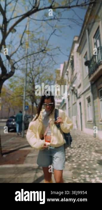 White woman strolling pastel avenue, sunlit facades and narrow ...