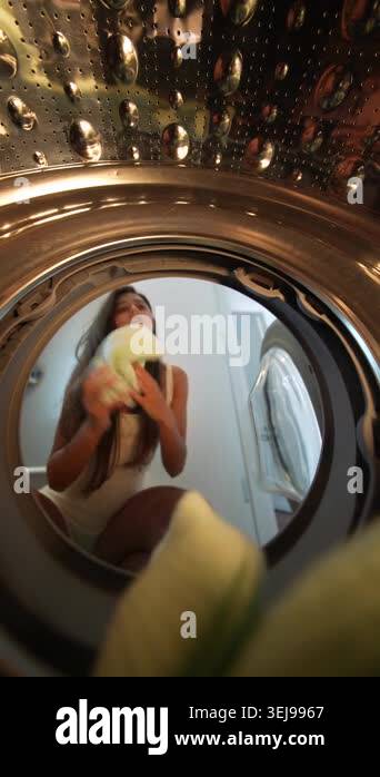 Inside washer drum woman retrieves towels, finishing chore with smile ...