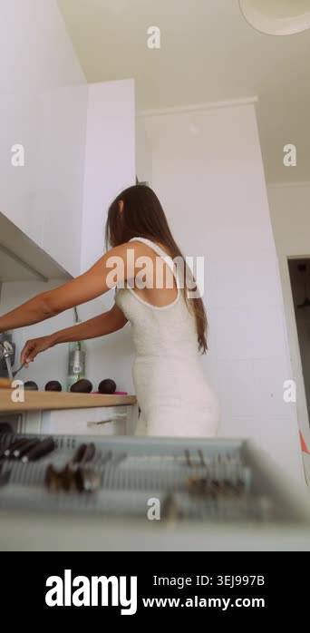 Drinking woman taking sip from glass while on phone, dishwasher open ...