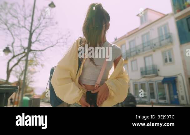 Young woman posing on city street wearing yellow jacket and sunglasses ...