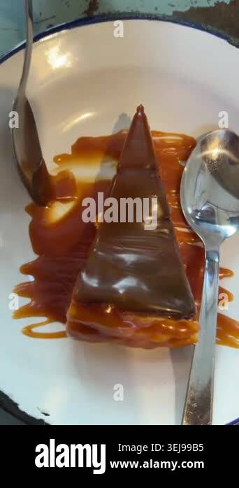 Caramel chocolate topped cake slice, enamel plate, spoon, rich glossy ...