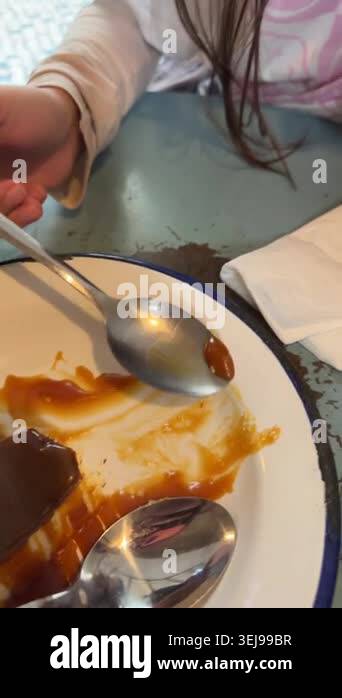 White girl eating caramel dessert while on phone, spoon and plate ...