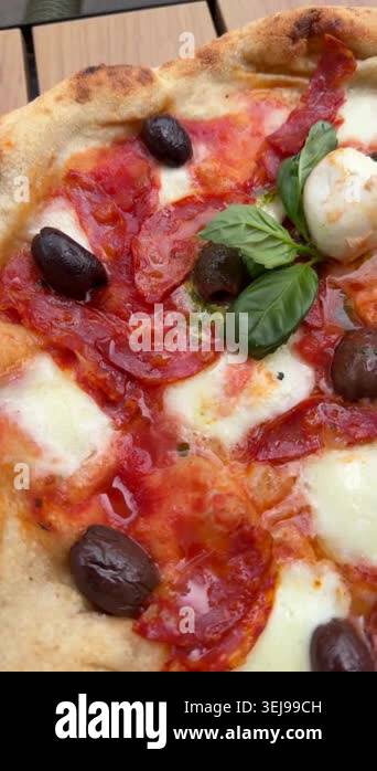 Closeup salami and olive pizza topped with fresh mozzarella pearls and ...