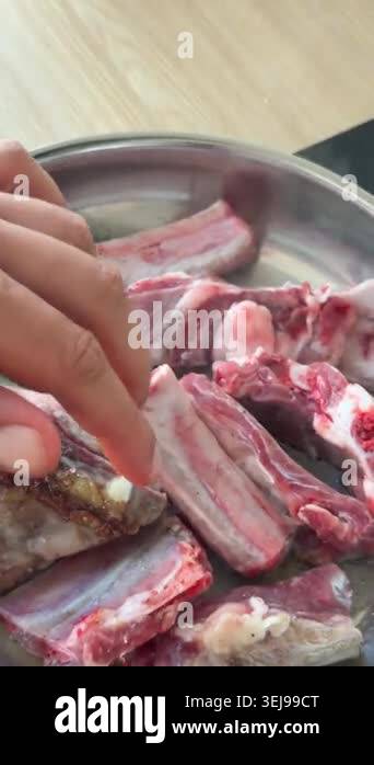 Careful arrangement of seared pork ribs in pan, small knife and spatula ...