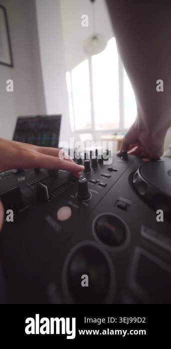 White DJ reaching over mixer and turntable under bright window closeup ...