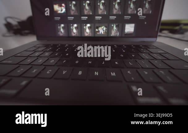 Close up laptop keyboard showing image thumbnails, moody desk lighting ...