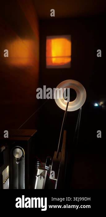 Closeup reel drive and amber projection on wall, engineer calibrating ...