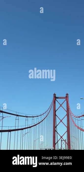 Red suspension bridge against clear sky, towering red tower with ...