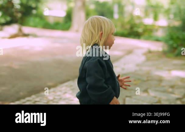 Blonde caucasian toddler offering green leaf to smiling woman on park ...