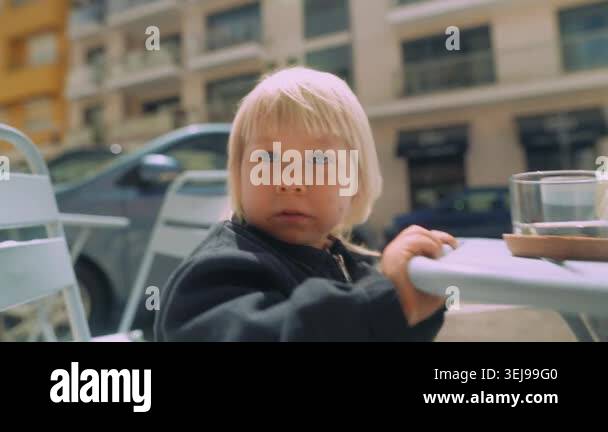 White toddler turning head in breeze, hair flying, candid outdoor cafe ...