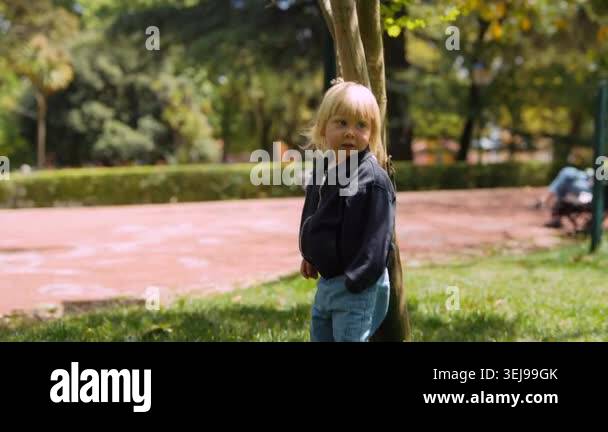 Young girl snacking under tree. Brighthaired toddler receives snack ...